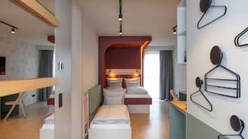 Quarto de hotel moderno com uma cama, mesas de cabeceira, uma escrivaninha e luminária fixada na parede.