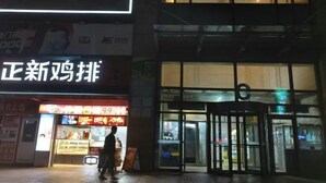 Um edifício com uma placa de 'Family' e um restaurante chamado '正新鸡排' com letreiros iluminados.