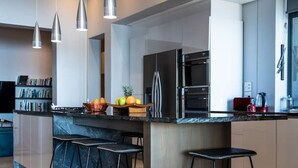 Uma cozinha moderna com ilha central, luminárias pendentes e banquetas de bar.