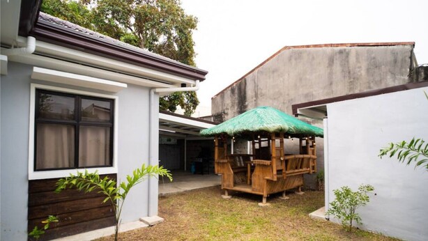 Uma casa com um pequeno jardim, um banco de madeira e uma cobertura de palha.