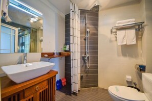 Casa de banho com lavatório suspenso, chuveiro e sanita.