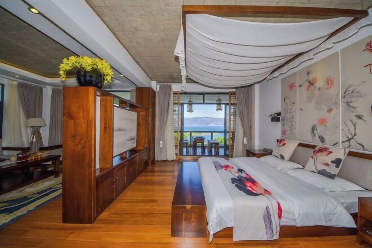Quarto com uma cama grande, móveis de madeira, vista pela janela e uma varanda.
