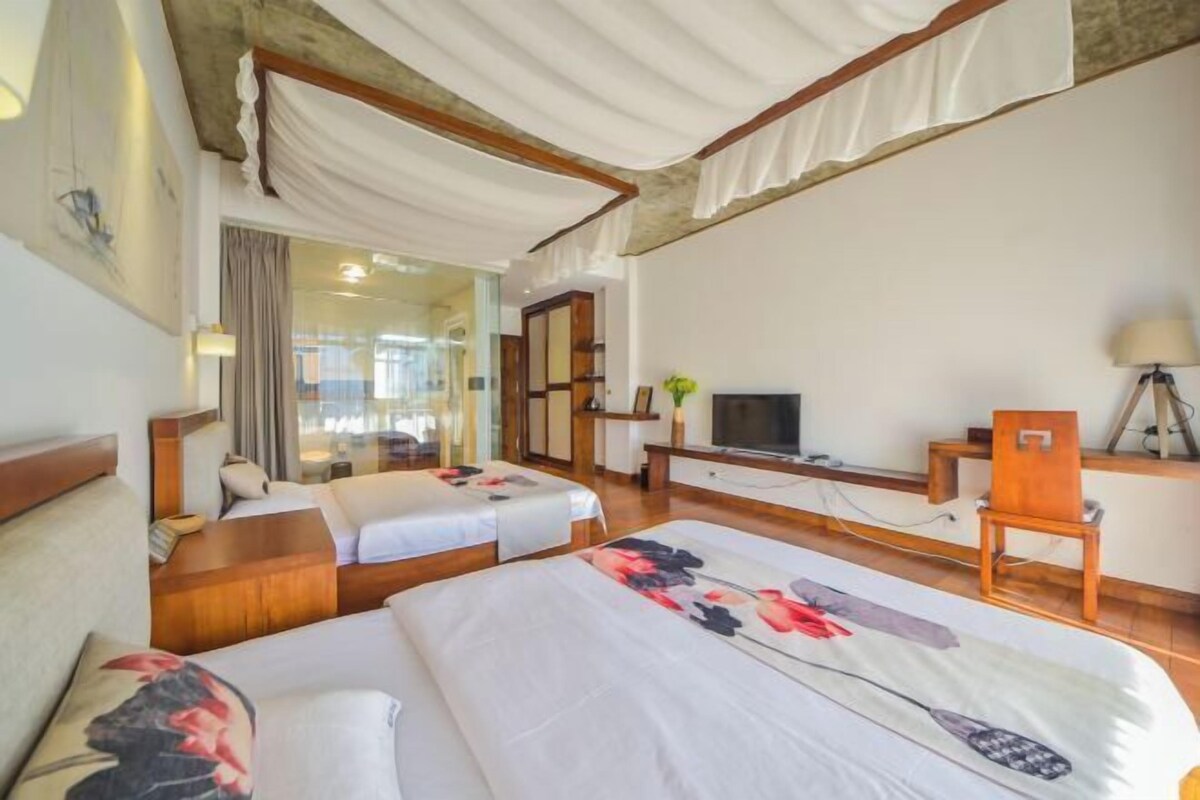 Quarto de hotel com duas camas, televisão, escrivaninha e espelho.