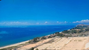Vista costeira com praia, estrada e povoado com edifícios.