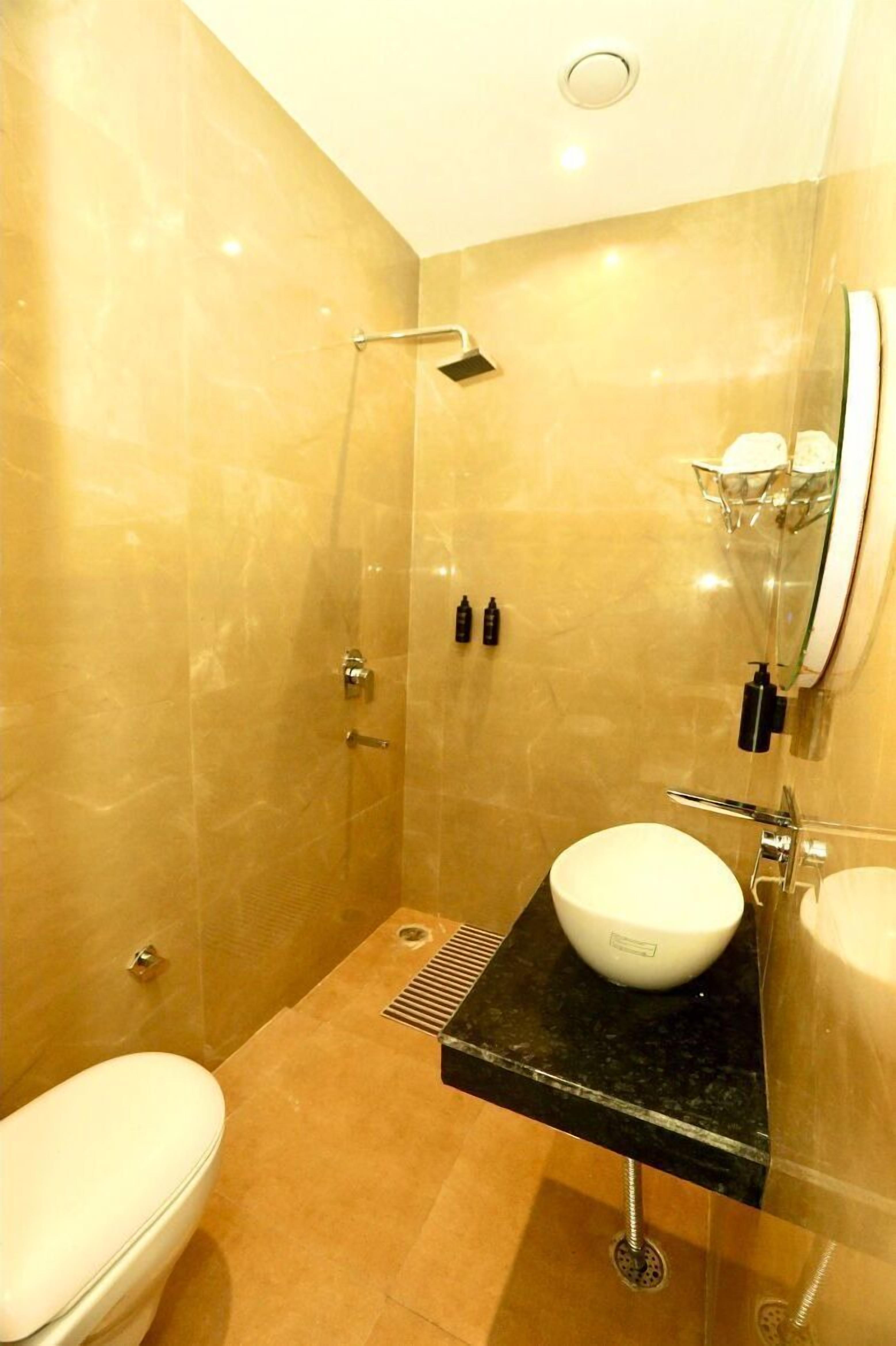 Uma casa de banho moderna com chuveiro, sanita e lavatório.