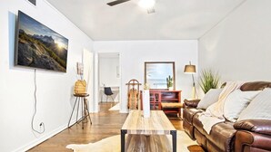 Uma sala de estar com mesa de centro de madeira, sofá de couro e televisão na parede.
