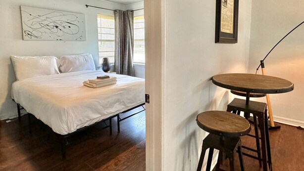Quarto com cama, ventilador de teto, janela com cortinas e um quadro na parede.