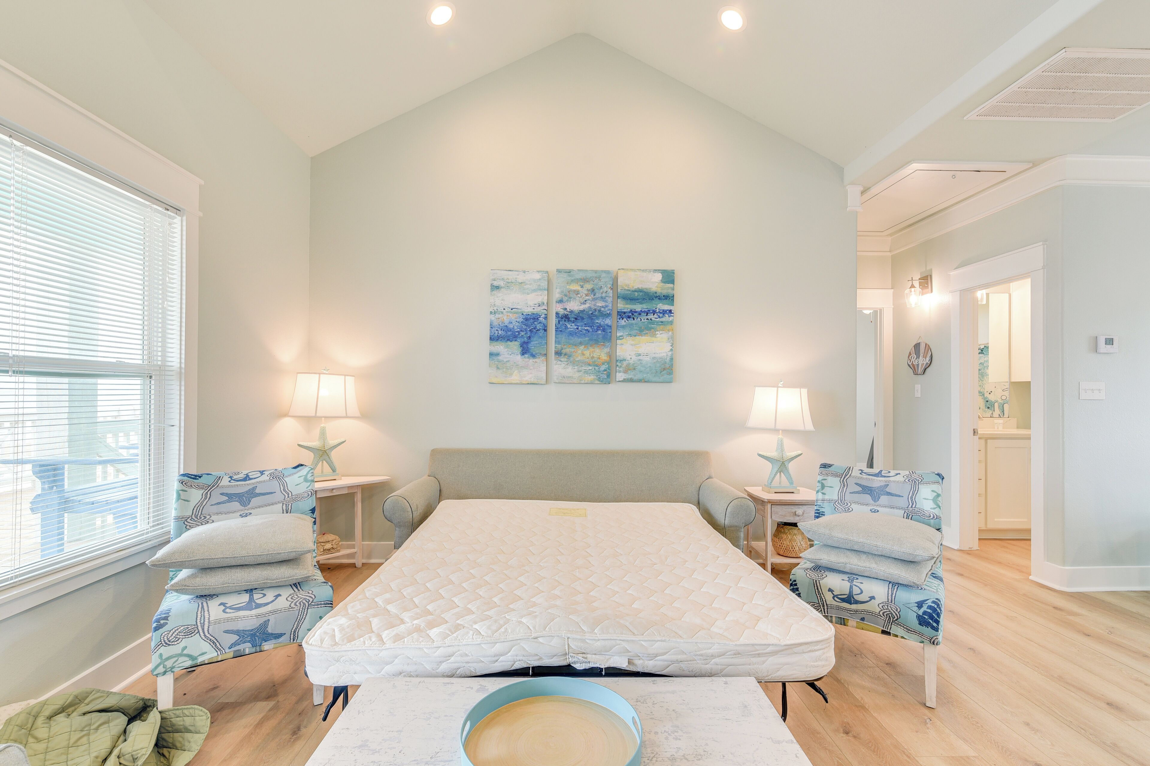 Quarto com uma cama grande, duas poltronas iguais, uma decoração em formato de estrela do mar e vista para o banheiro ao lado.