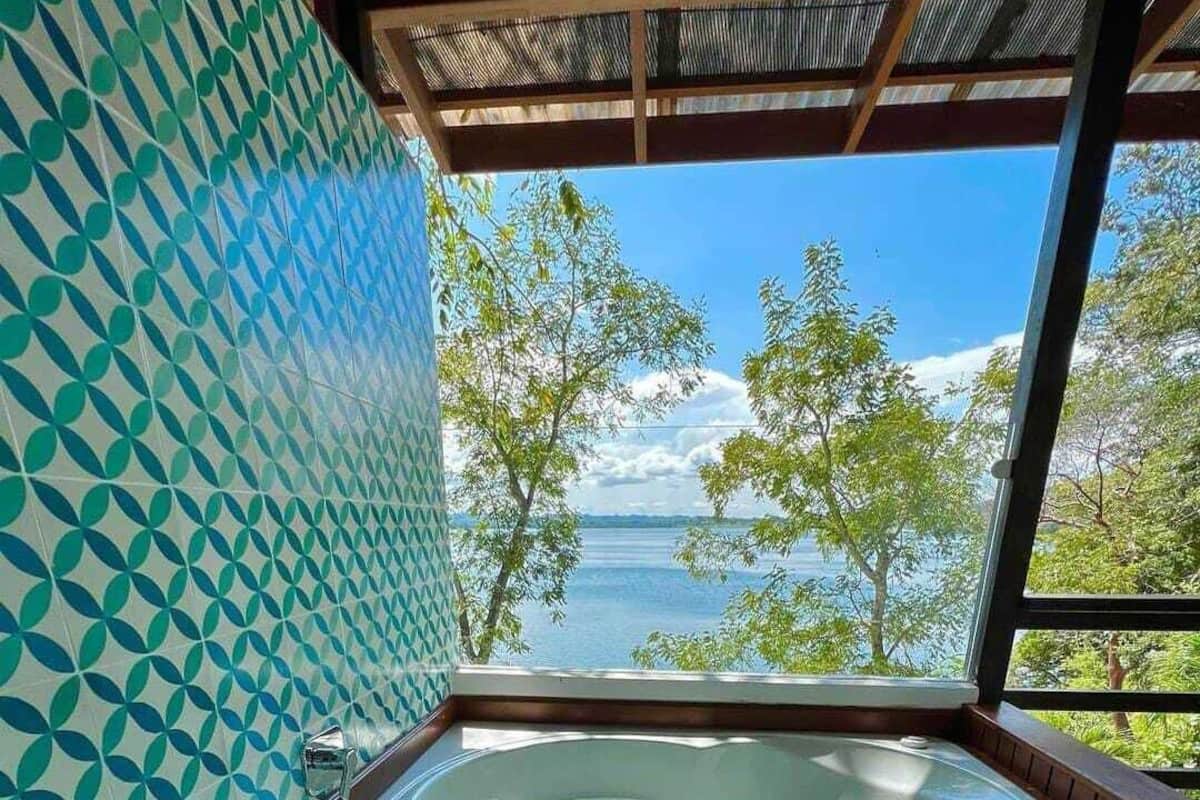 Uma banheira de hidromassagem com vista desobstruída para um lago e árvores.