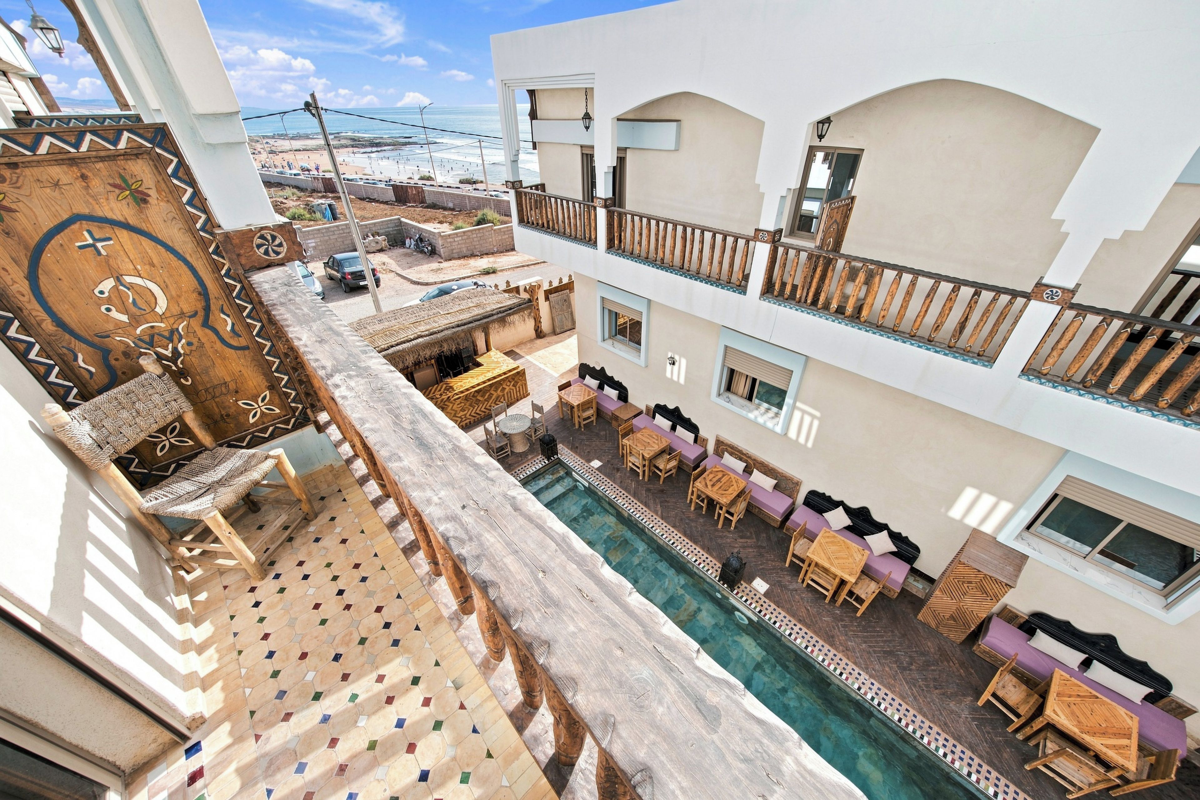Um deque externo em vários níveis com piscina, áreas de estar e vista para a praia.