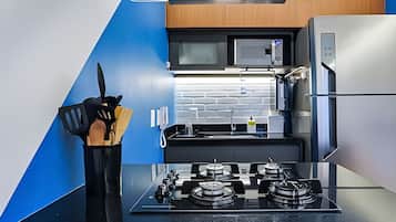 Cozinha moderna com bancada preta, eletrodomésticos de aço inoxidável e uma parede com detalhes em azul.