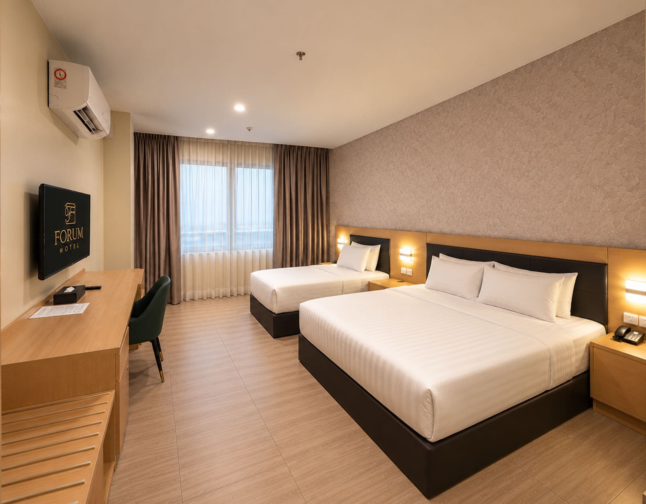 Quarto de hotel com cama, mesas de cabeceira, escrivaninha, cadeira, televisão e janela com cortinas.
