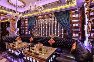 Uma sala de estar luxuosa com um sofá de couro preto, uma mesa de centro de vidro e decoração requintada.