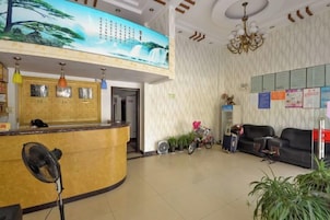 Um saguão de hotel com balcão de recepção, área de estar e um grande mural na parede.