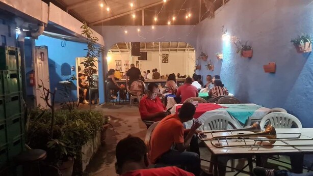 Restaurante com mesas e cadeiras, algumas ocupadas por clientes.