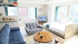 Quarto de hotel moderno com sofá, poltrona, mesa redonda e uma cama.