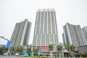 Um edifício alto com vários andares, rodeado por palmeiras e vegetação.