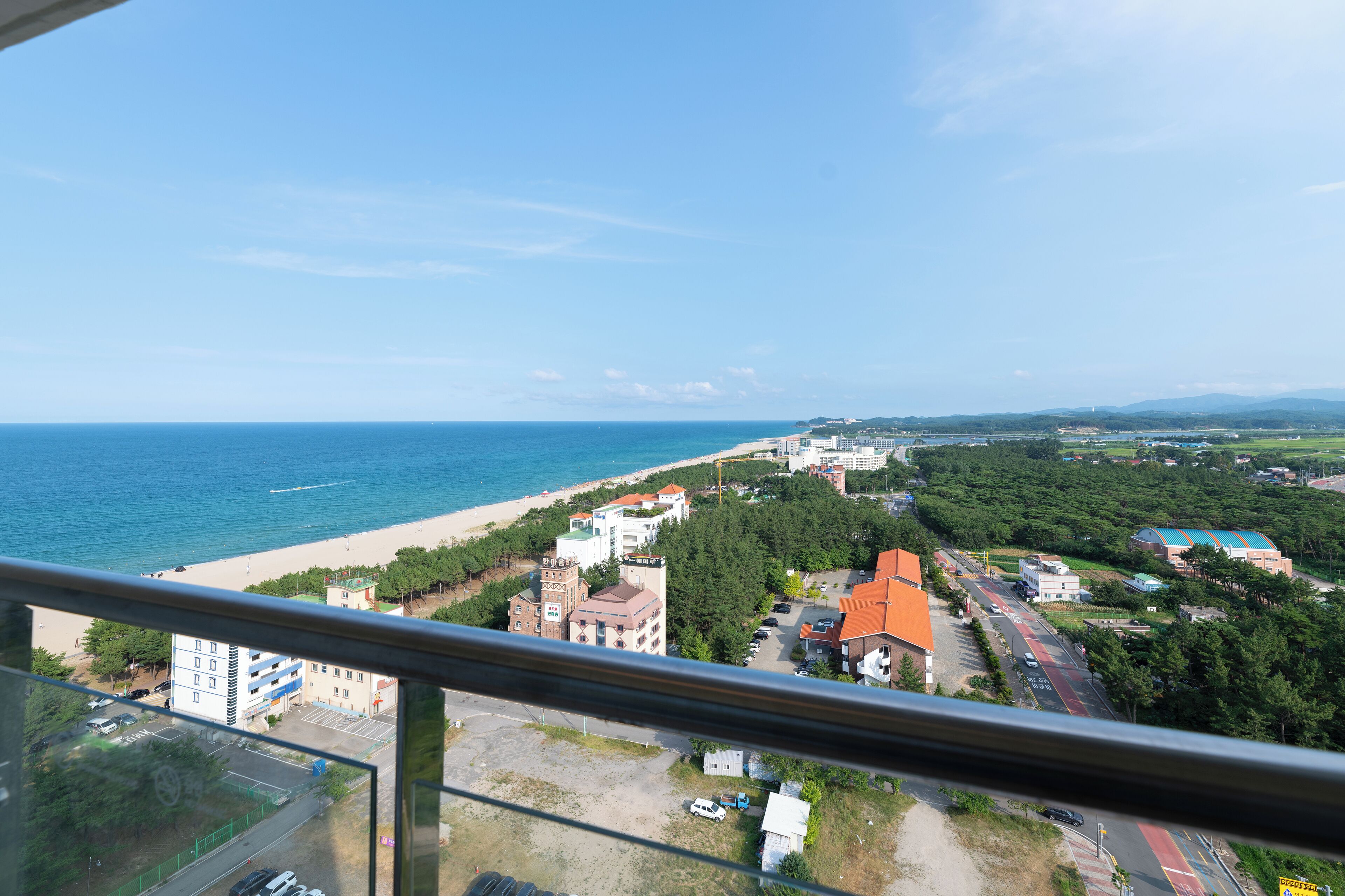 Paisagem costeira com praia, edifícios e céu claro.