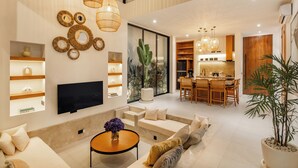 Uma sala de estar moderna com televisão, sofá, mesa de centro e obras de arte decorativas na parede.