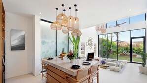Cozinha ampla com uma ilha grande, luminárias pendentes modernas e vista para o exterior.