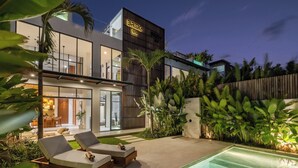 Uma casa moderna com piscina, cadeiras de descanso e um jardim bem cuidado.