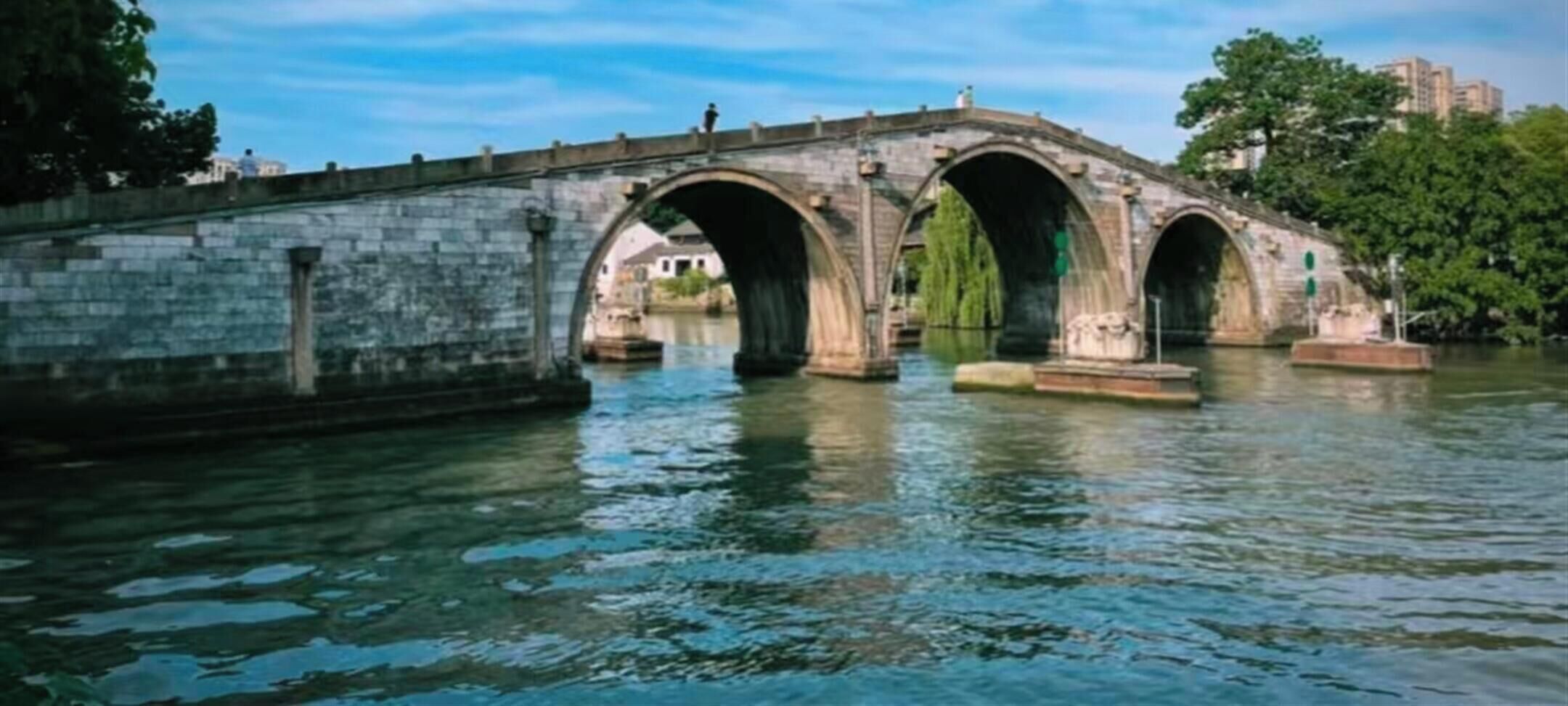 Uma ponte de pedra com três arcos sobre um corpo de água.