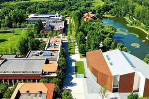 Um edifício moderno com telhado plano, rodeado por um gramado bem cuidado e um corpo de água.