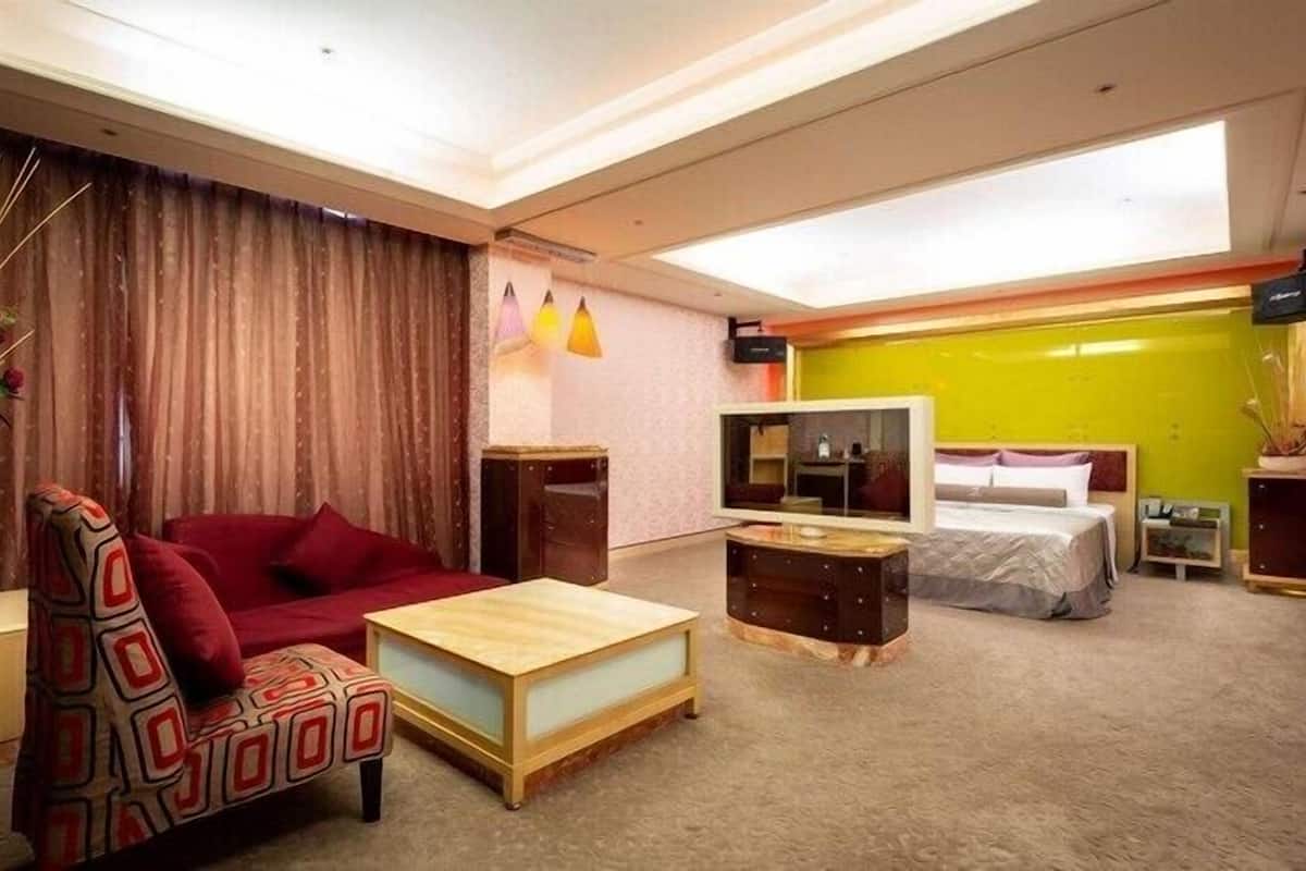 Quarto de hotel moderno com sofá, televisão, cama e uma pequena mesa.