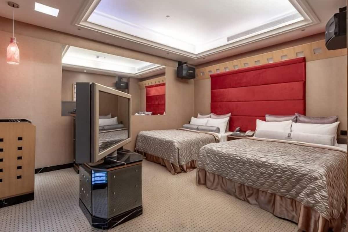 Quarto de hotel com duas camas, televisão, espelho e luminária no teto.