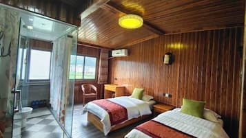 Quarto com painéis de madeira, duas camas, uma escrivaninha e cabine de hidromassagem de vidro.