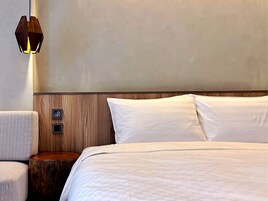Quarto de hotel com uma cama, duas mesas de cabeceira e uma luminária na parede.