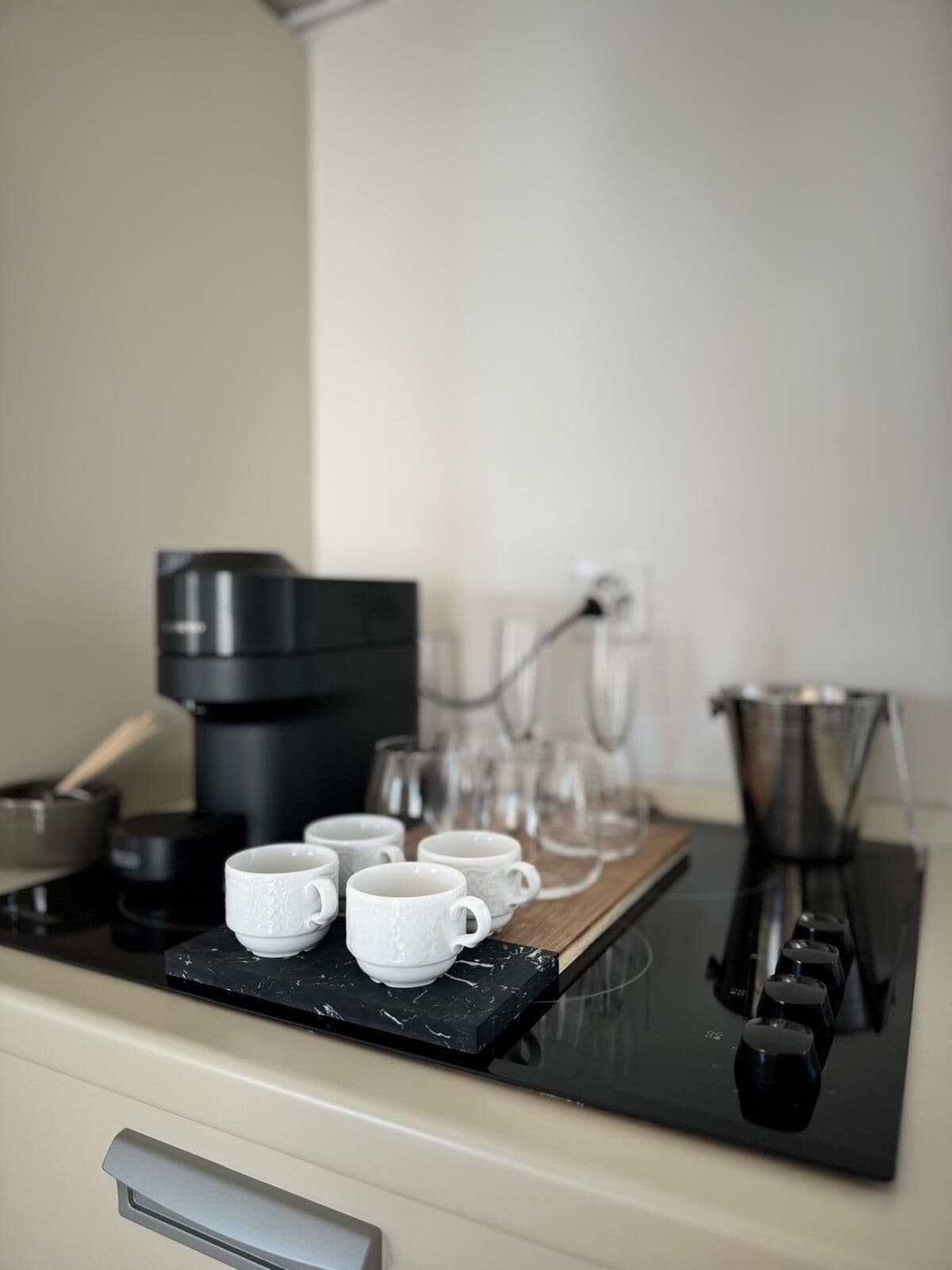 Uma máquina de café com uma bandeja de xícaras brancas e uma garrafa de café em uma bancada.