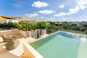 Piscina no terraço com vista ampla dos edifícios e áreas verdes ao redor.