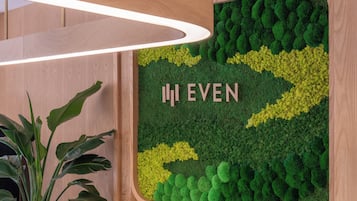Uma parede com textura semelhante a musgo, em tons de verde e amarelo, e a palavra "EVEN" ao centro.
