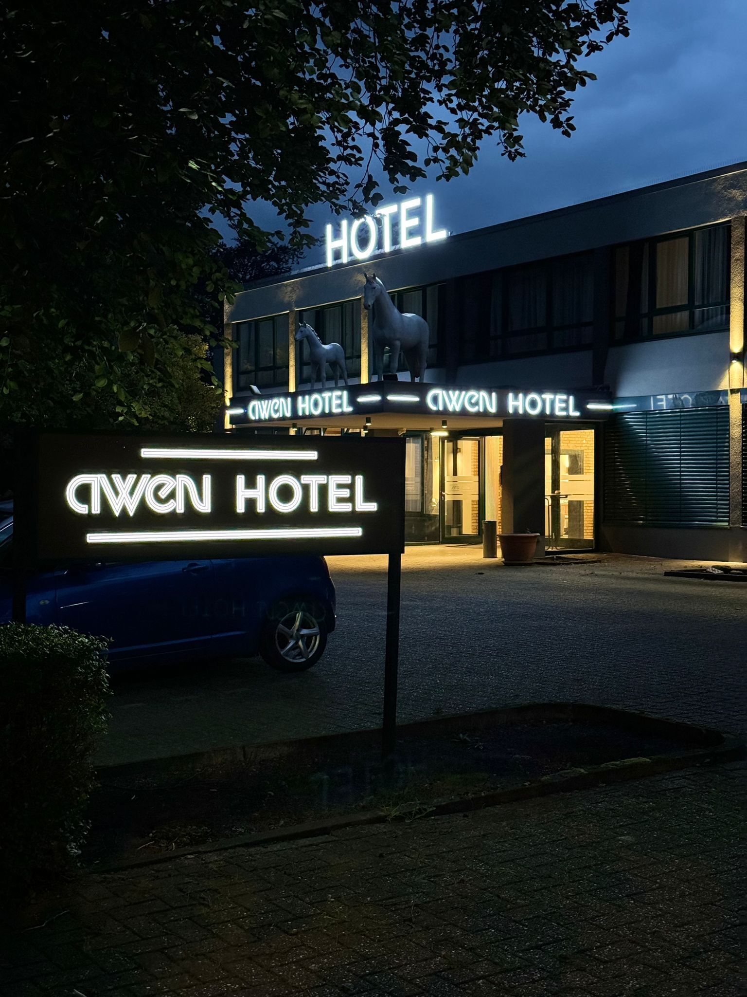 Placa do Hotel Ciwon com um letreiro de neon e duas estátuas de cavalos no telhado.