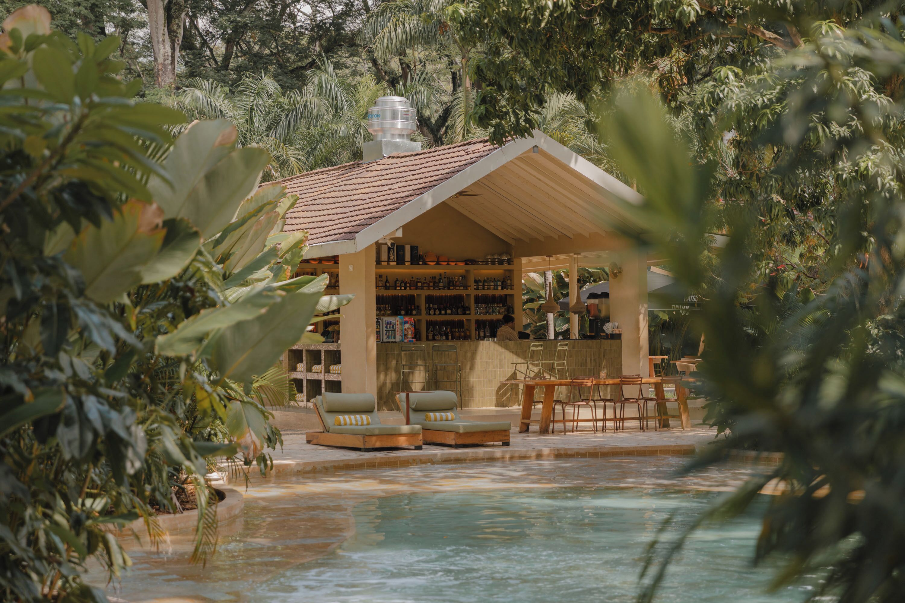 Área à beira da piscina com espreguiçadeiras e bar.