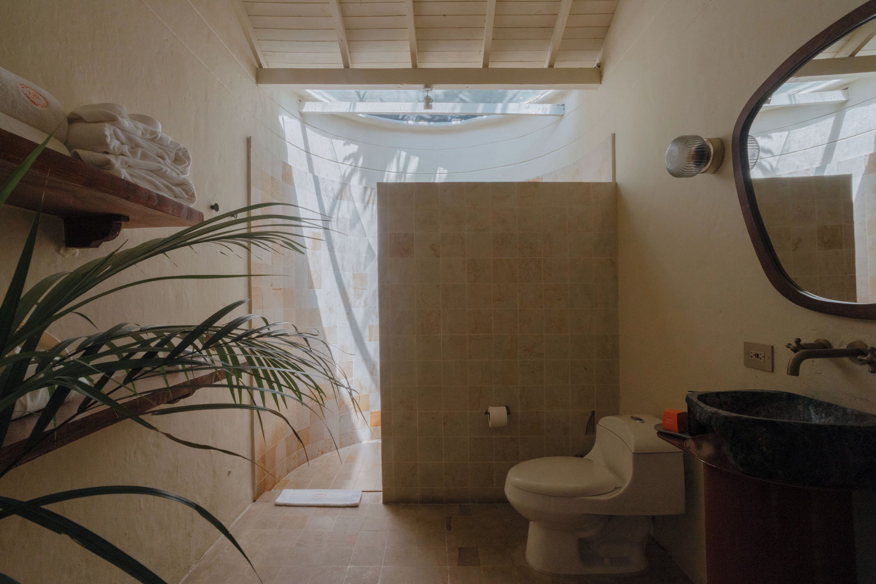 Casa de banho com sanita, lavatório, espelho e zona de duche.