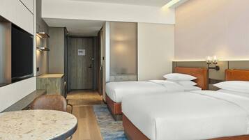 Quarto de hotel com cama, mesas de cabeceira, televisão e área de estar.