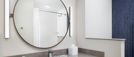 Casa de banho moderna com um espelho redondo, uma sanita e um porta-toalhas.