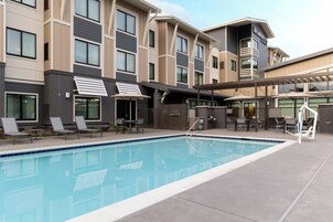 Um hotel moderno com piscina, área de estar ao ar livre e um terraço coberto.