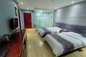 Quarto de hotel com duas camas, uma escrivaninha de madeira, uma televisão e uma porta vermelha.