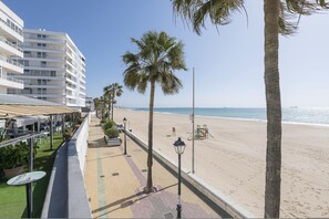 Um hotel à beira-mar com calçada, palmeiras e vista para a praia.