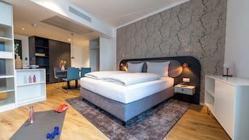 Quarto moderno com uma cama grande, mesas de cabeceira, uma escrivaninha e uma cadeira.