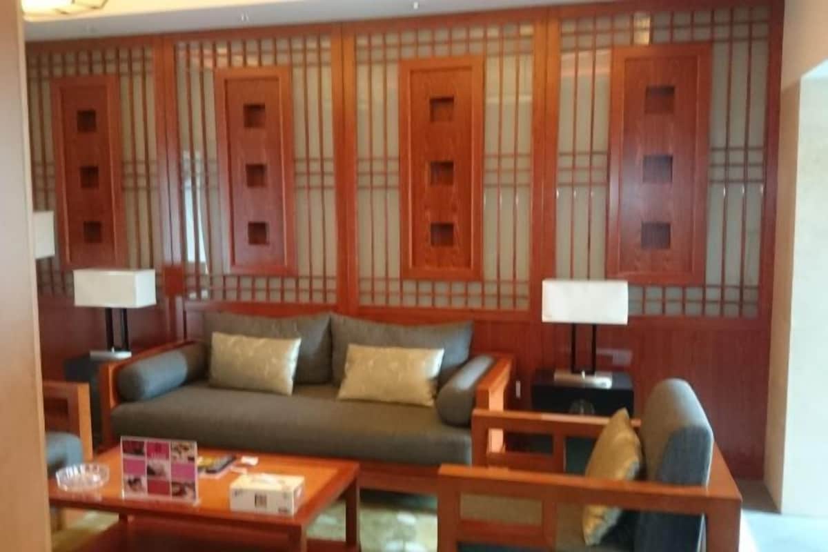 Sala de estar com sofá, poltronas, mesa de centro e um divisório tradicional de madeira com janelas.