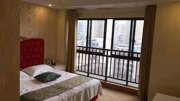 Quarto de hotel com uma cama grande, uma mesa de cabeceira e uma janela com vista para edifícios.