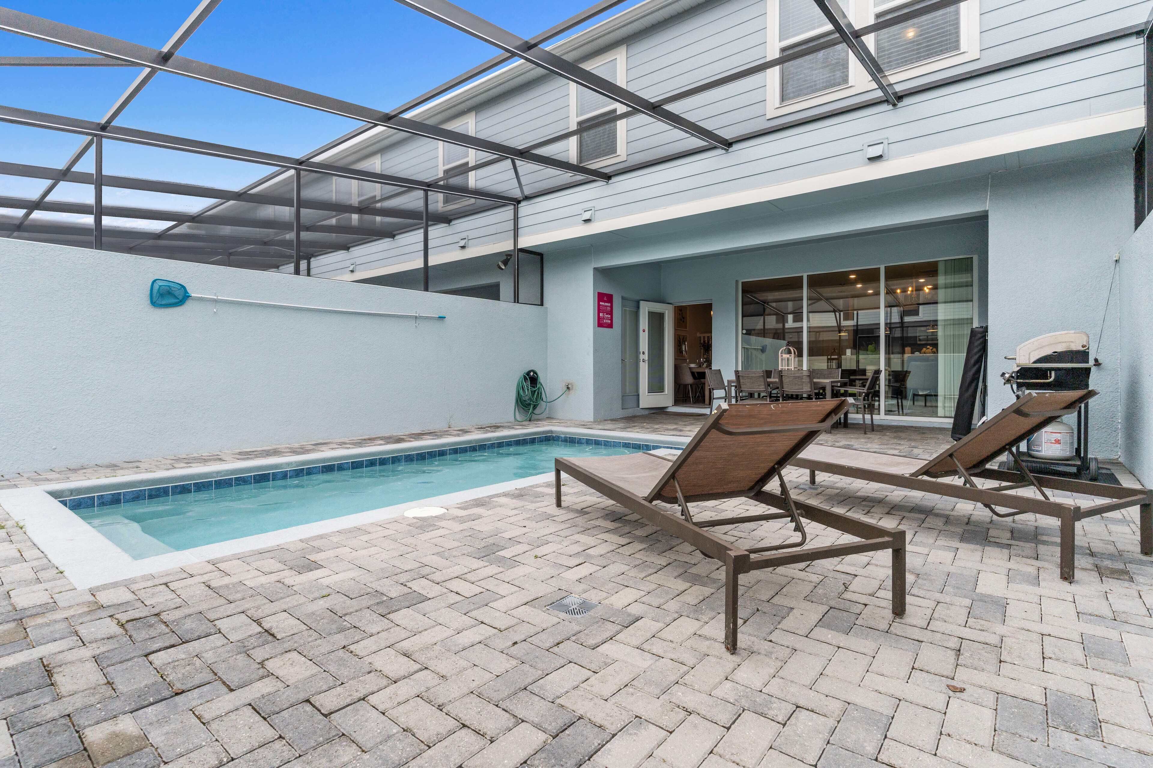 Piscina externa com espreguiçadeiras, um terraço coberto e vista do interior através de portas de vidro.