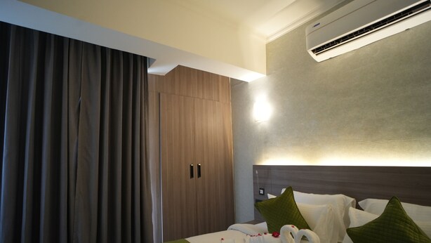 Quarto de hotel com cama, cortinas, unidade de ar condicionado e luminária.