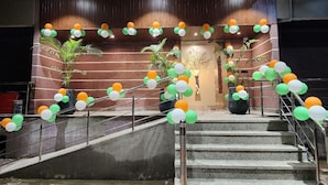 Uma escadaria com balões verdes, brancos e laranja, que leva a uma parede de madeira com uma placa.