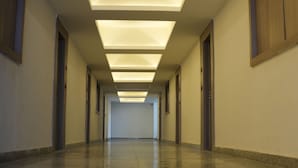 Um corredor longo e bem iluminado, com piso polido e iluminação embutida no teto.