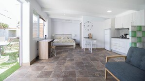 Um espaço de estar moderno e aberto, com cama, escrivaninha e kitchenette.